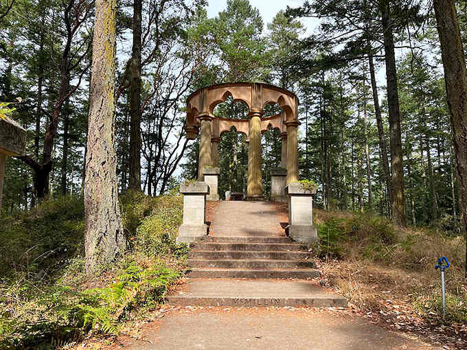 Stone steps rise through quiet Pacific Northwest pines toward something that feels borrowed from ancient Rome and dropped into the forest.