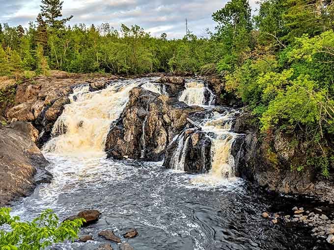 The Kawishiwi River tumbles golden and wild over ancient rock, looking absolutely untamed under a dramatic northern sky.