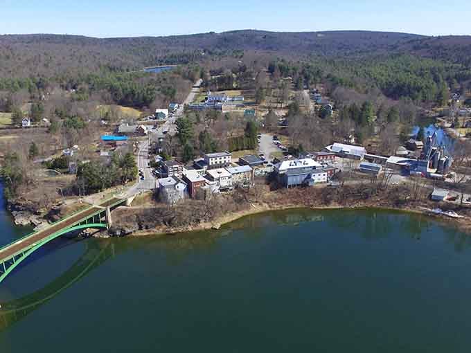 Bird's-eye view reveals a lakeside village cradled by forested hills, where nature and community exist in perfect harmony.