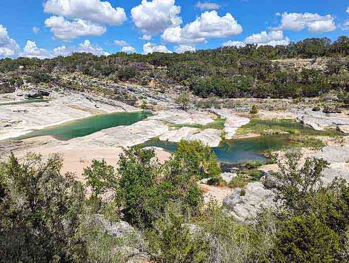 Emerald pools nestle among white limestone shelves, creating natural swimming holes that stay refreshingly cool year-round for visitors.