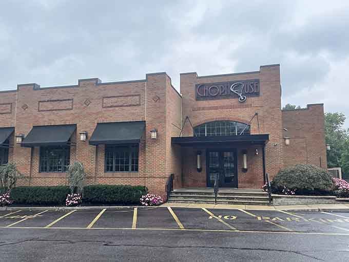 Solid brick, black awnings, and pink flowers at the entrance — The ChopHouse exterior quietly signals that something exceptional waits inside.