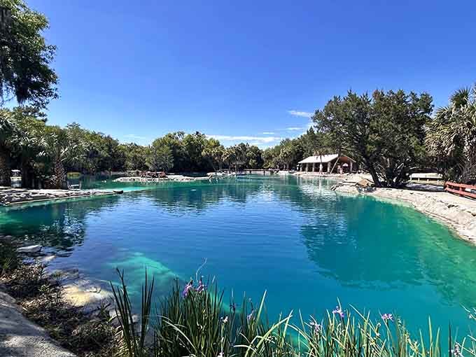 That mirror-flat turquoise surface stretching toward a rustic pavilion is the kind of scene that makes you cancel all your other weekend plans.