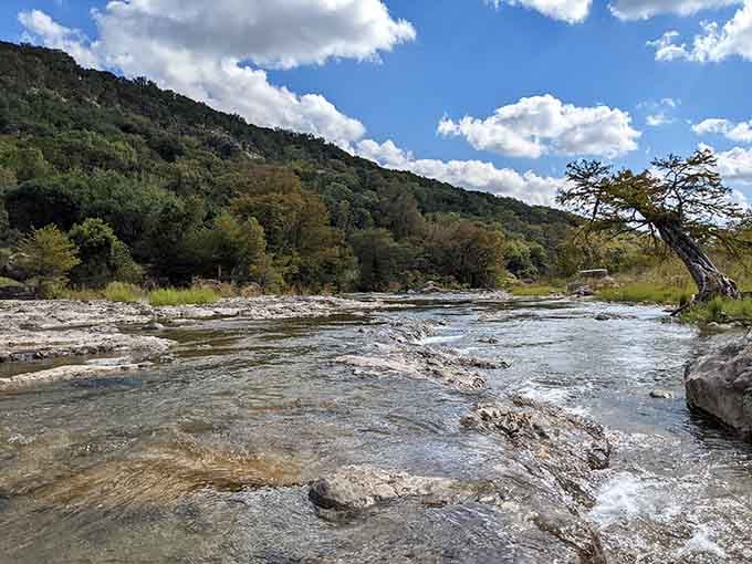 The river cascades over layered rock formations, flowing like liquid glass through a landscape carved by patient water.
