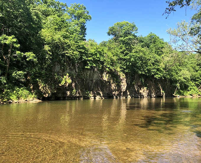 Sunlit bluffs mirror perfectly in the Big River's glassy surface, nature showing off without any apology whatsoever.