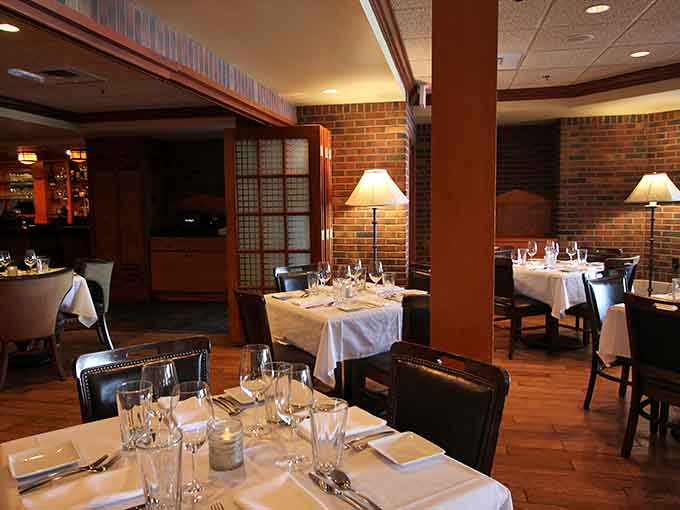 Warm lamp glow, white linens, exposed brick, and polished stemware — The ChopHouse dining room is where a great evening begins.
