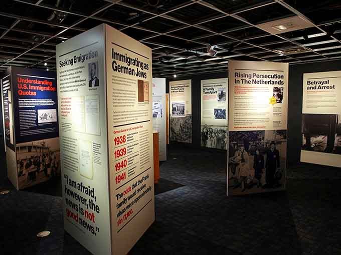 Stark exhibit panels rise from the darkness, each one carrying words that demand you stop, read, and remember.