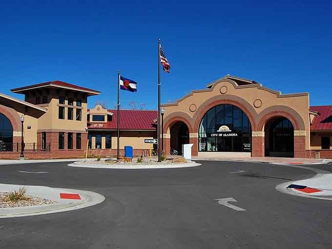 The City of Alamosa's adobe-style city hall stands proudly under twin flags, looking like it means serious, cheerful business.