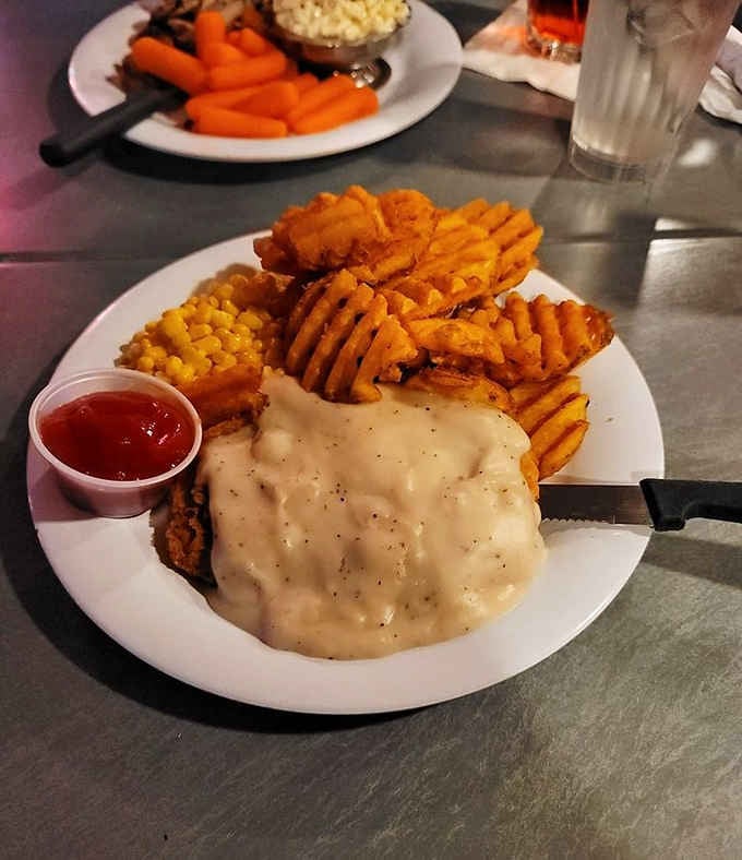 Chicken fried steak blanketed in creamy country gravy, with sweet potato fries and corn on the side. Comfort, plated beautifully.