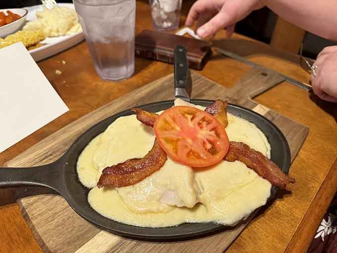 The Hot Brown arrives in a cast iron skillet, bubbling with cheese sauce, bacon, and tomato. Kentucky on a plate.