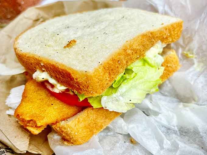 A fish sandwich on soft white bread with lettuce and tomato. Straightforward, generous, and completely unapologetic about being absolutely delicious.