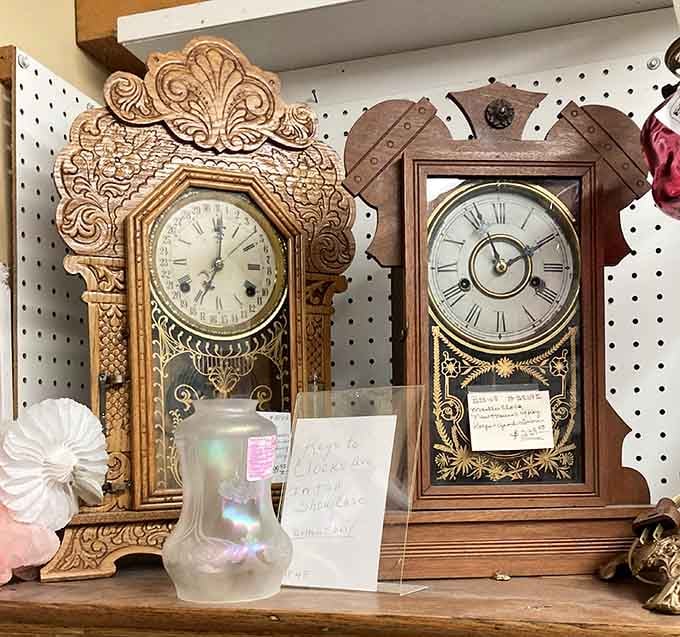 Two ornate mantel clocks sitting shoulder to shoulder, their carved wooden cases telling stories that no digital display ever could.