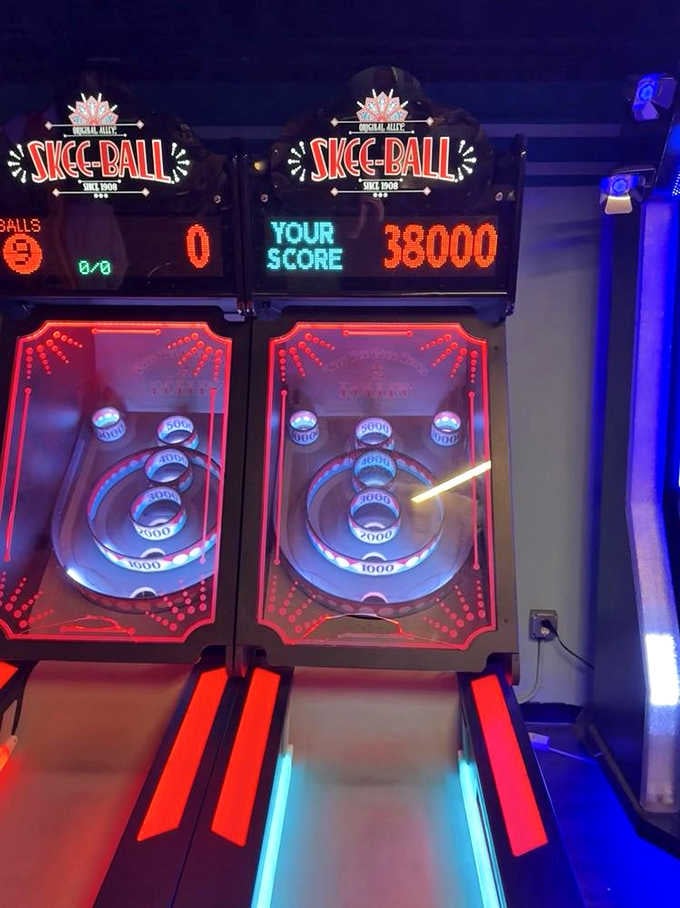 Skee-Ball machines glowing red and blue, because rolling a ball into a hole never gets old, ever.