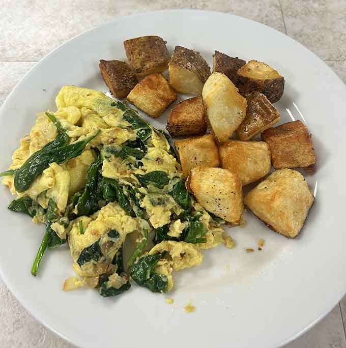 Golden breakfast potatoes alongside perfectly scrambled eggs with greens, the kind of plate that makes you slow down.
