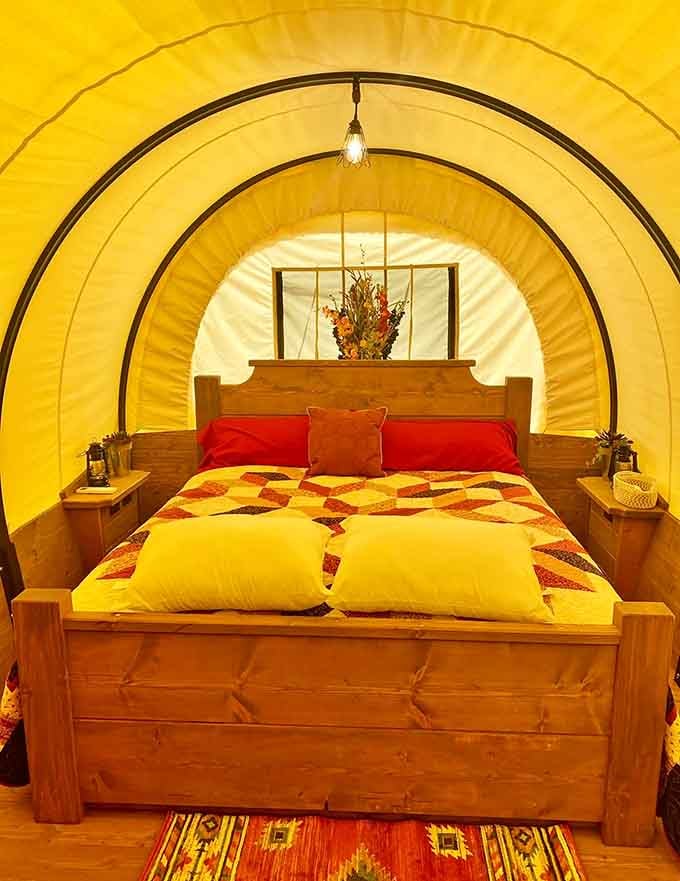 Red pillows, a patchwork quilt, and a wooden bed frame. Sleep like a very comfortable pioneer tonight.
