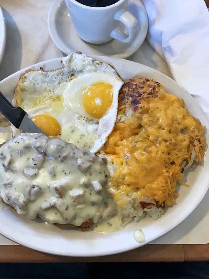 Biscuits drowning in sausage gravy, two sunny-side eggs, and cheese-smothered hash browns, breakfast as a full commitment.