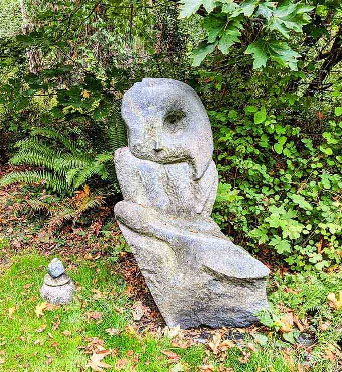 This thoughtful stone owl perched among the ferns looks like it's been quietly judging every visitor's life choices since the beginning of time.