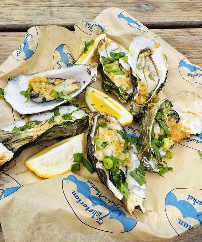 Grilled oysters on the half shell, topped with green onion and cilantro, with lemon wedges ready to go. Pure Pacific magic.