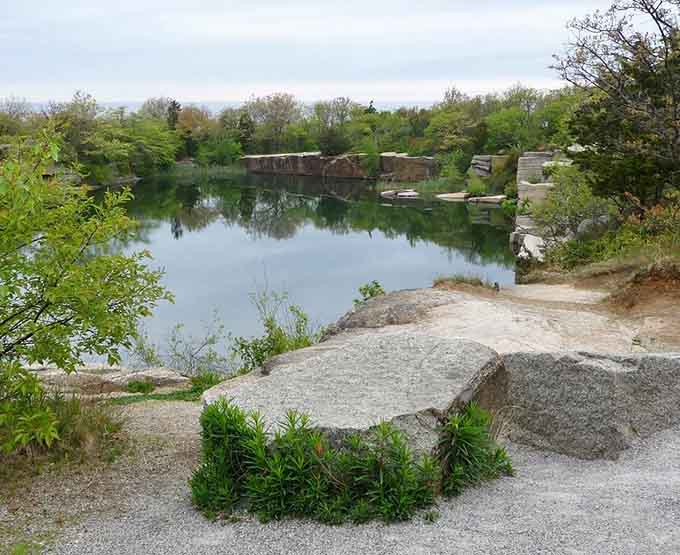 Abandoned granite blocks rest beside impossibly clear water, nature's patient reclamation project creating accidental beauty from industrial history's leftovers.
