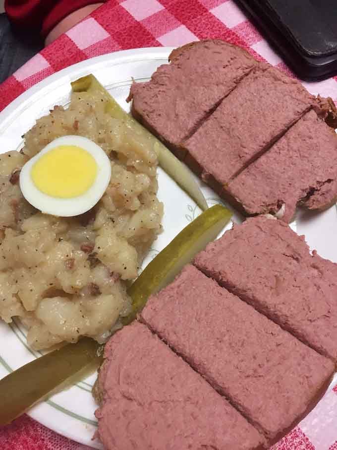 Liverwurst on a plate with potato salad and pickles, old-world comfort food done without apology.