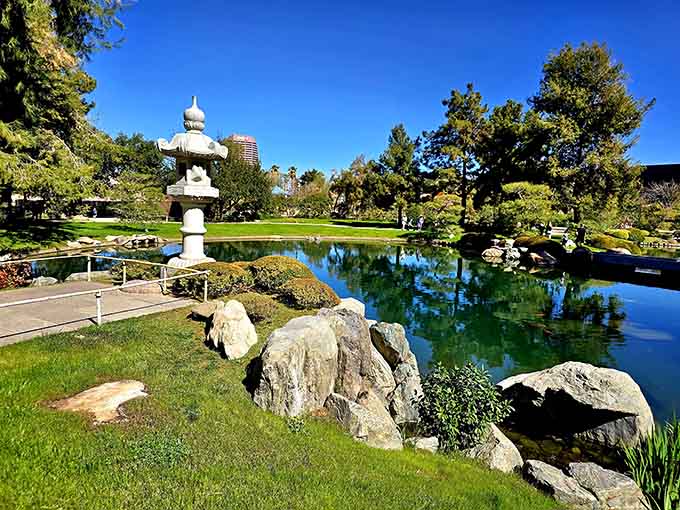 That stone lantern standing tall against a mirror-perfect pond is the kind of scene that makes you put your phone away. Almost.