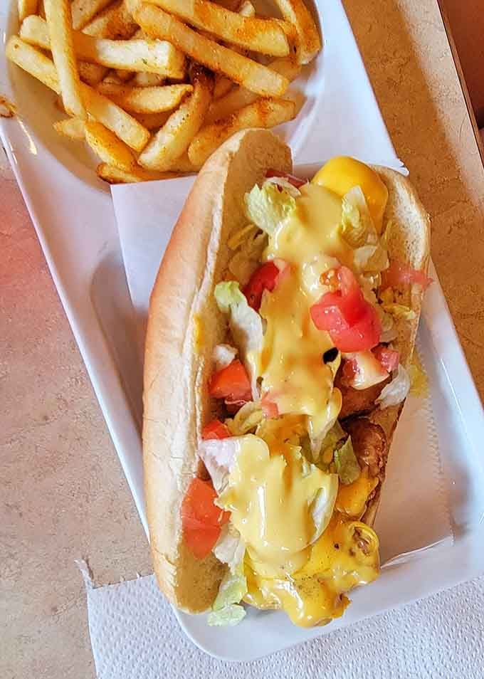 That cheese cascade over a loaded hot dog is basically edible sunshine on a bun with fries.
