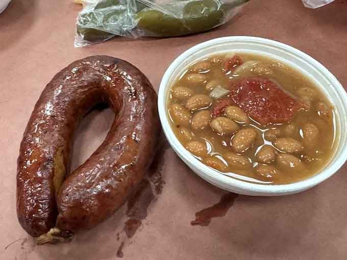 A glossy sausage link beside a bowl of pinto beans. Simple, honest, and deeply satisfying in every possible way.