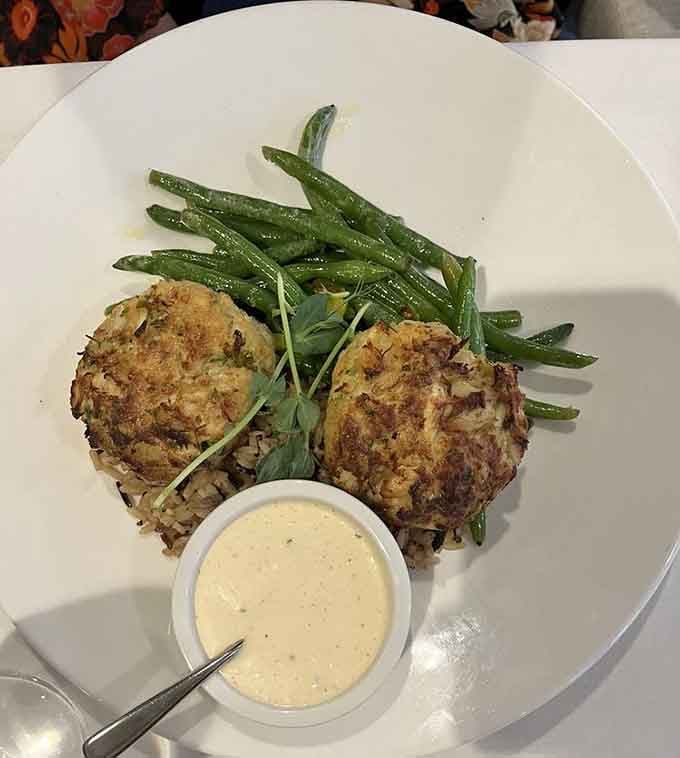 Two golden crab cakes, crisp green beans, and a ramekin of remoulade that earns its place.