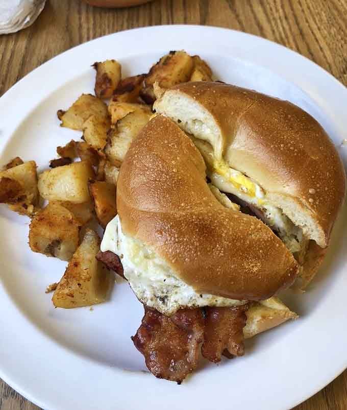 A breakfast sandwich on a bagel with crispy bacon and home fries, because some mornings call for serious reinforcements.