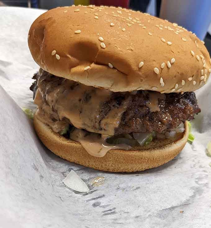 That thick, charbroiled patty with melted cheese spilling over the edges is pure, unapologetic burger perfection.