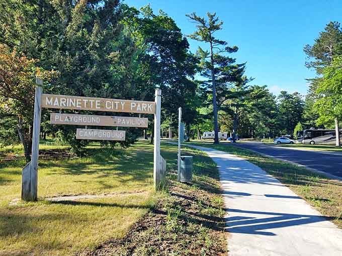 Tall pines frame the entrance to Marinette City Park, where the sign promises a playground, pavilion, and campground all in one welcoming package.