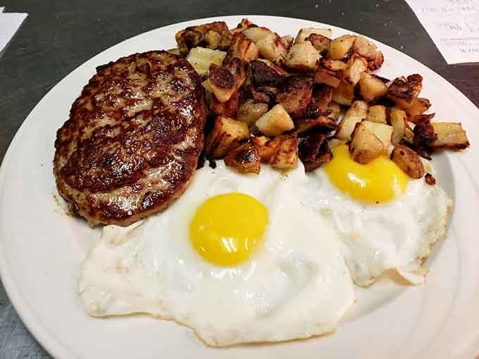 Two sunny-side-up eggs, a sausage patty, and a mountain of home fries. Morning has never looked this confident.