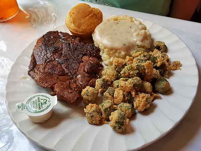 A seared steak, creamy mashed potatoes, fried okra, and a fresh roll, Southern comfort food dressed up and ready to impress.