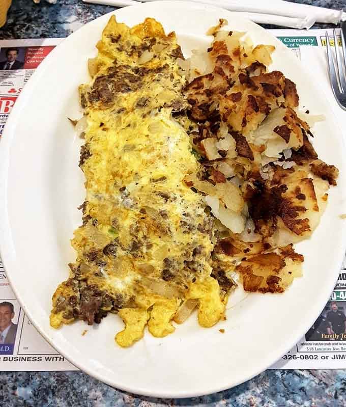 A cheesesteak omelette with crispy home fries alongside it is proof that breakfast never needs an excuse.