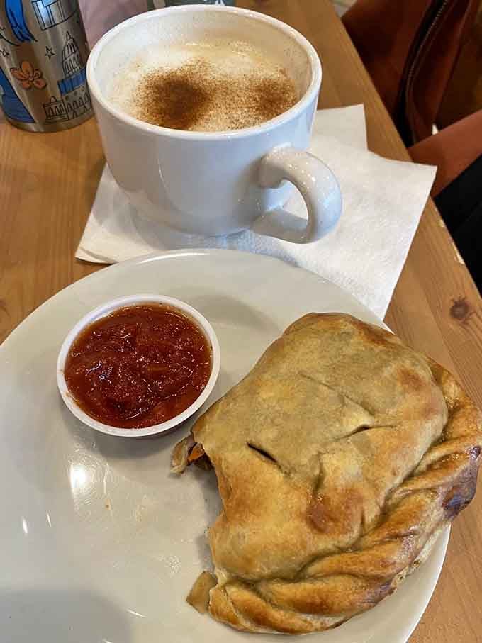 A golden, flaky handpie served alongside a rich dipping sauce and a perfectly dusted cappuccino. Comfort food, elevated just enough.