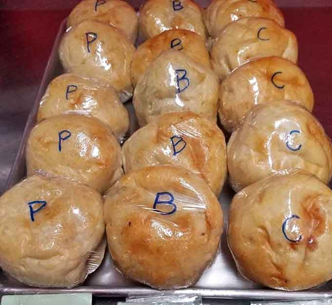 Golden, plump, and labeled with a single letter, these baked buns are the quiet overachievers of the entire display case.