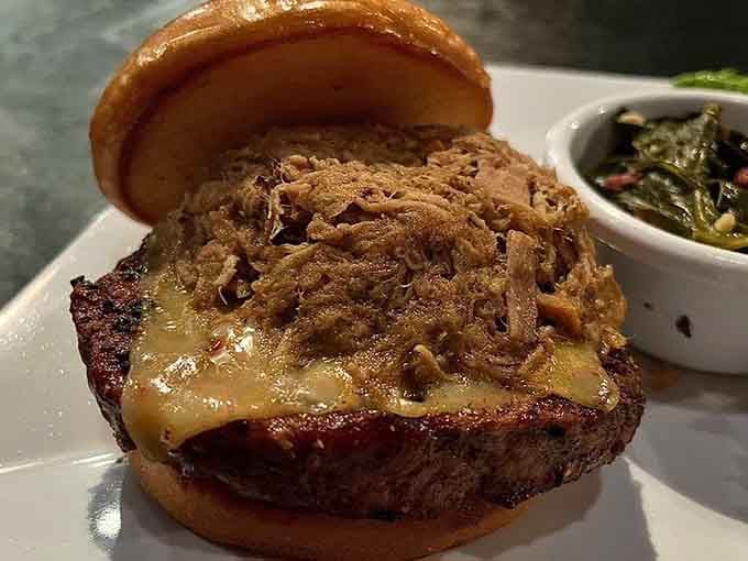 A burger topped with melted cheese and pulled meat, served alongside greens. Dinner just became an occasion.