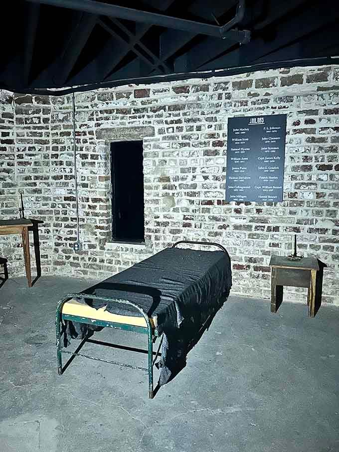 A bare iron bed and a list of jailers on the wall. Sleep tight.