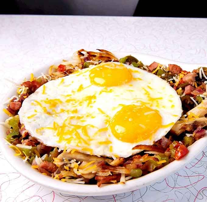 Two sunny-side eggs crowning a loaded skillet of vegetables and meat. Breakfast just got a promotion.