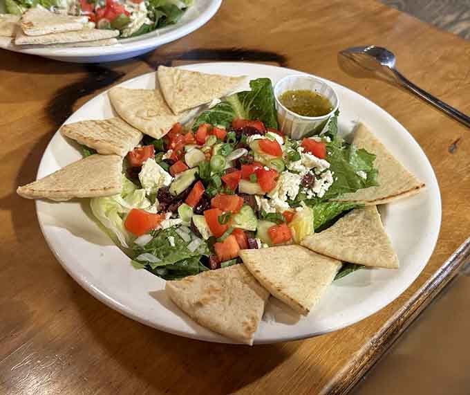 The Greek salad with fried pita triangles arranged just so, like a little edible sunburst on a wooden table.