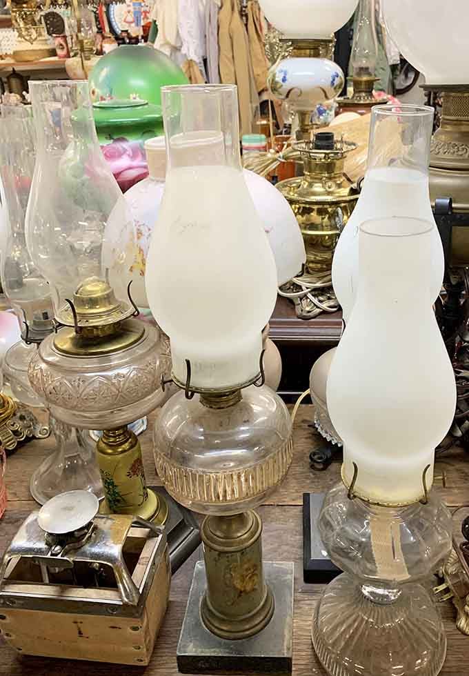 Antique oil lamps cluster together like old friends, each one glowing with quiet, frosted-glass elegance.