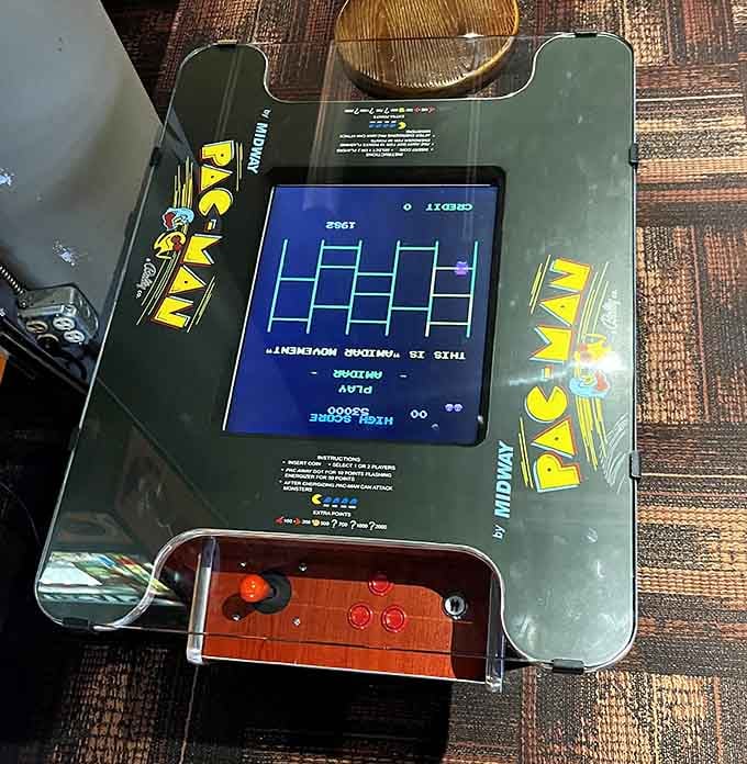A classic Pac-Man cocktail cabinet sits ready, proving that some legends never need an upgrade or an apology.