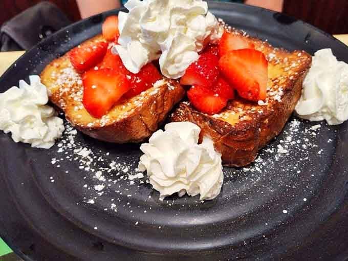 Thick French toast buried under fresh strawberries and clouds of whipped cream. Dessert called, breakfast answered.
