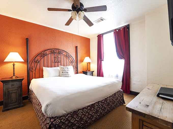 Burnt orange walls and an ornate iron headboard make this room feel like a painting you get to sleep inside.