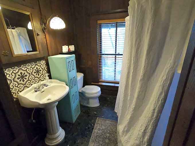Vintage pedestal sink, patterned tile, and wood-paneled walls. This bathroom has more personality than most living rooms.