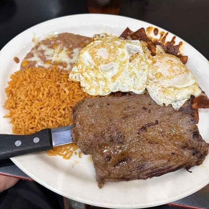 Steak, eggs, rice, and beans sharing one plate like old friends who've been doing this for years.