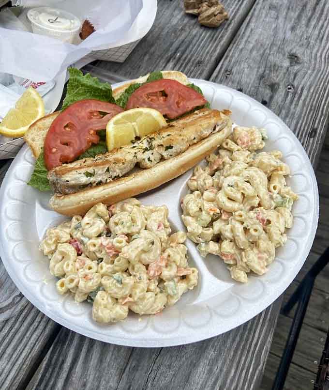A mahi-mahi sandwich dressed with lettuce, tomato, and lemon. Comfort food with serious waterfront credentials on the side.
