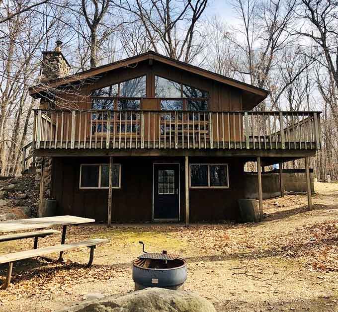 This sturdy cabin tucked among bare winter trees is basically a warm hug with a stone chimney and a deck.