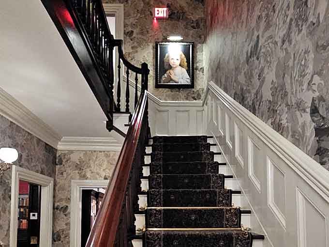 That staircase, with its dark carved runner and floral wallpaper, makes every ascent feel genuinely cinematic.