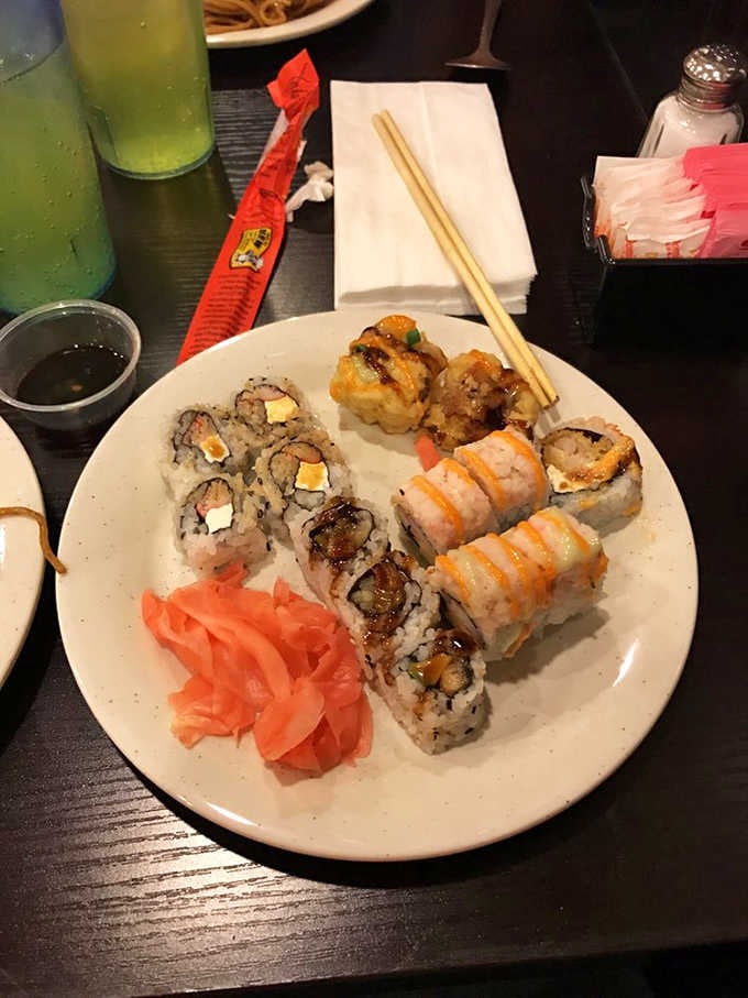 A sushi plate worth slowing down for. Drizzled rolls, pickled ginger, and chopsticks at the ready.