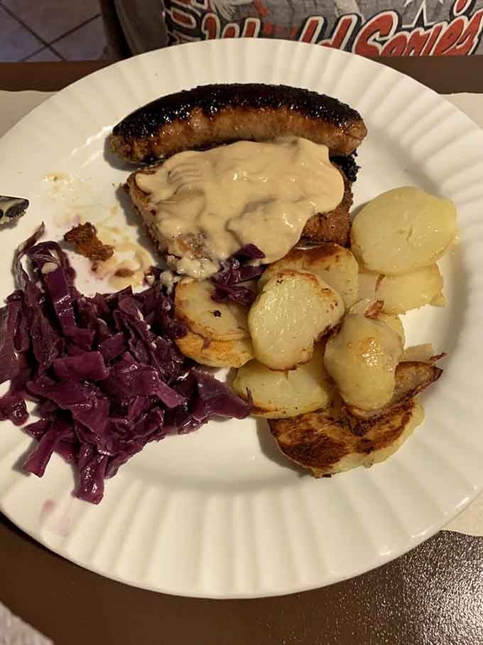 Schnitzel crowned with creamy mushroom gravy, a charred bratwurst on top, and golden fried potatoes alongside, this plate delivers pure joy.